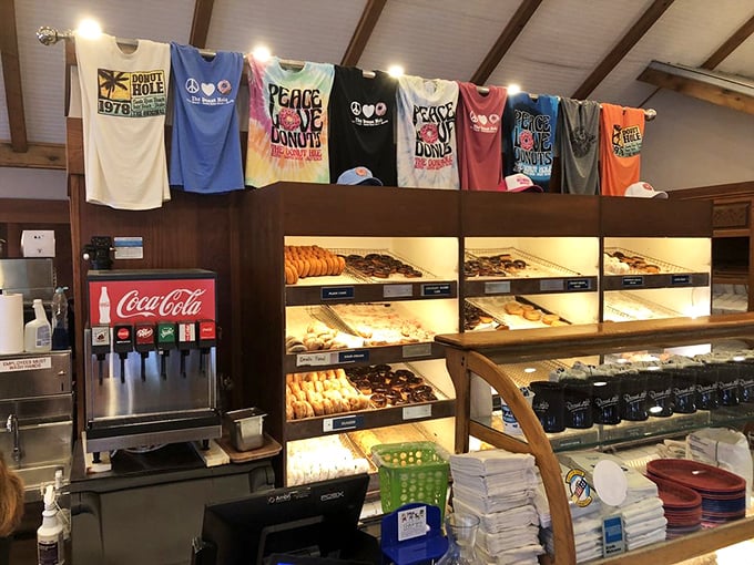 T-shirts hanging like colorful flags above a donut display that would make Homer Simpson weep with joy. Peace, love, and donuts indeed.