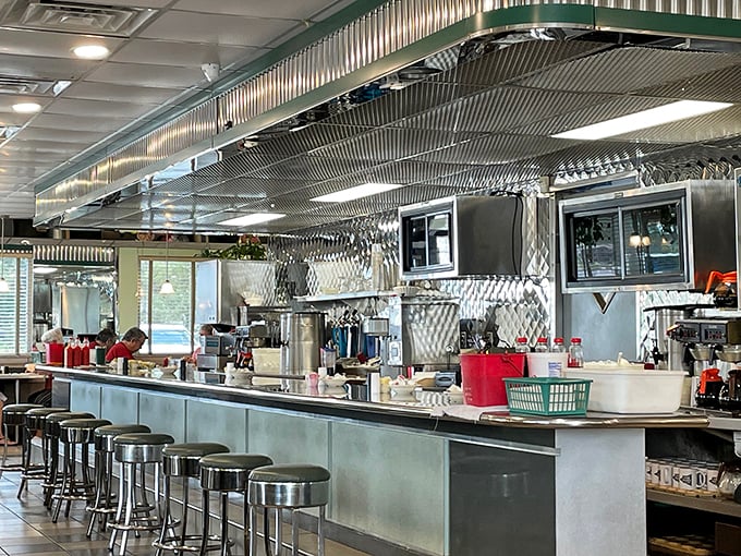 The gleaming counter with its row of stools is diner theater—where short-order ballet unfolds beneath the shine of stainless steel.