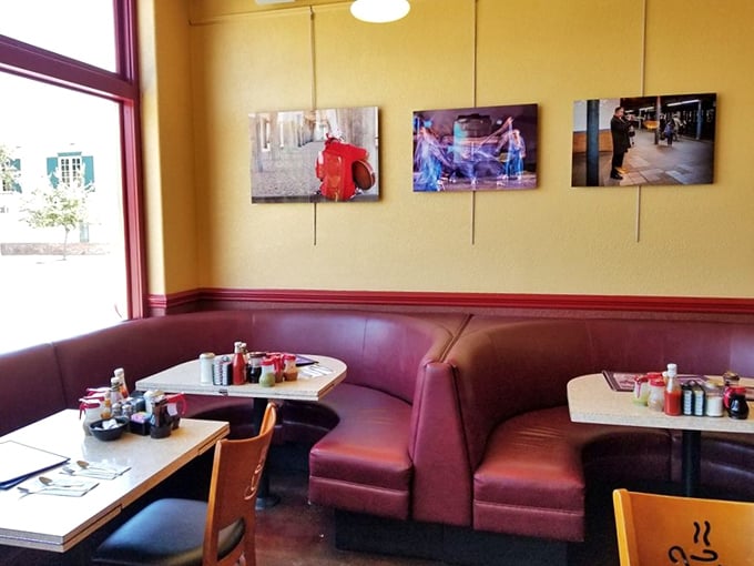 The burgundy booths aren't just seating—they're front-row tickets to the breakfast show. Yellow walls and art create that "neighborhood favorite" ambiance we all crave.