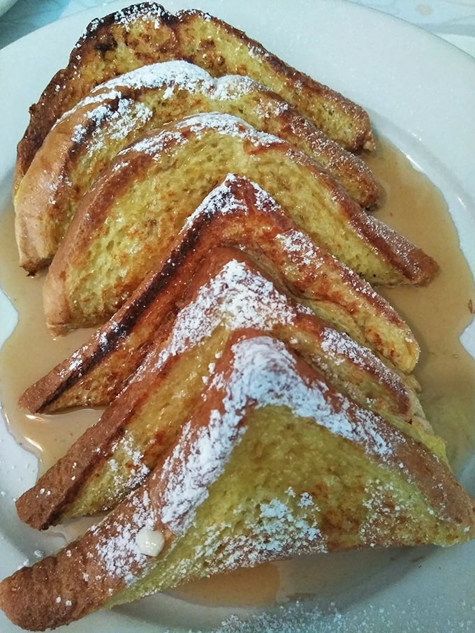 French toast that's achieved the golden ratio – crispy edges, custardy centers, and powdered sugar snow that melts on contact.