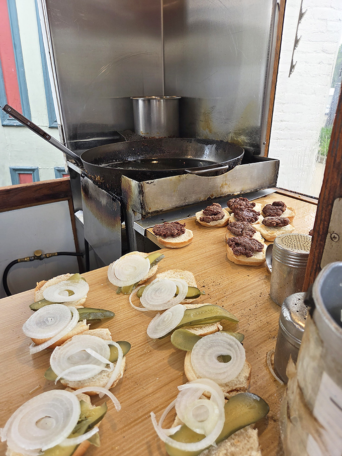 Behold the battlefield where burger greatness is forged. That seasoned skillet has more stories than your grandpa after three beers.