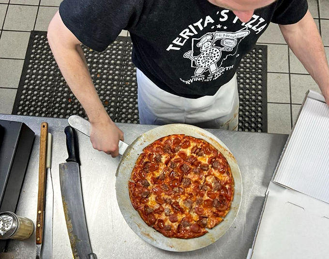 The pizza assembly line – where dough becomes art. Notice the practiced precision that comes from decades of perfecting the craft.