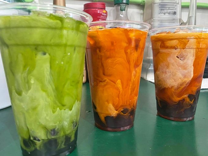Three milk teas standing like colorful soldiers—green, orange, and caramel—each promising a different path to refreshment heaven.