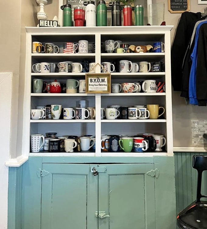 The mug wall—where coffee vessels come to retire and tell tales of conversations past. Note the "B.Y.O.M." sign!