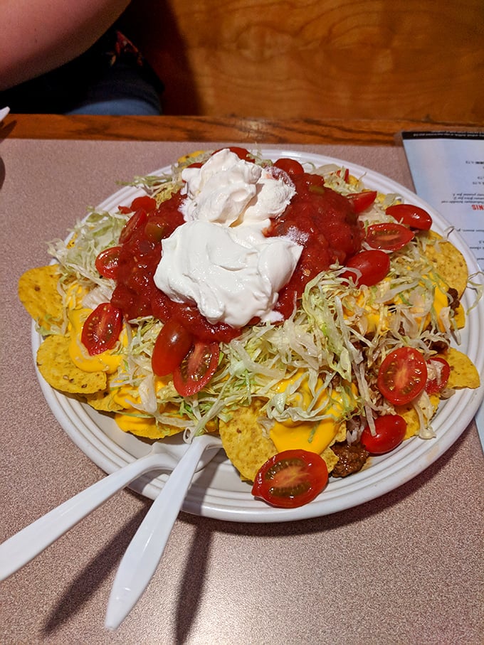 These nachos aren't just a snack, they're an architectural achievement—layers of chips, cheese, and toppings crowned with dollops of sour cream and salsa.