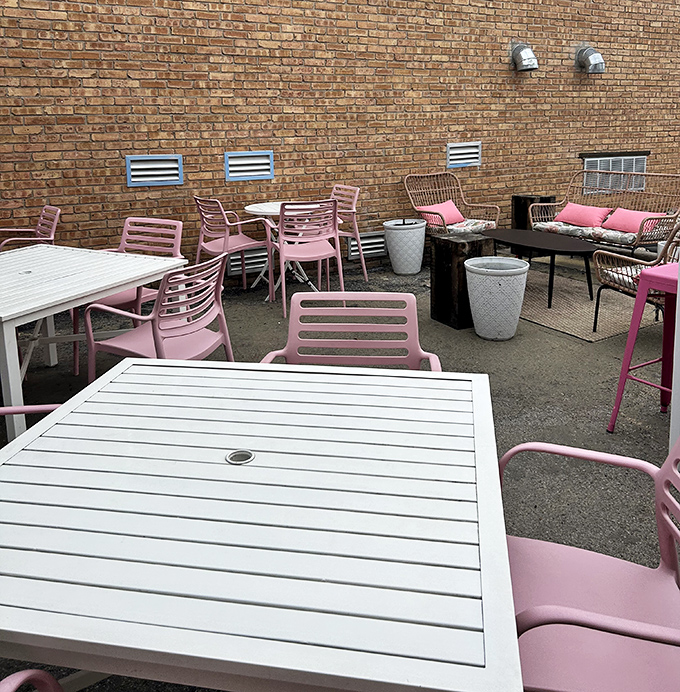 The brick-walled patio offers an urban oasis for burger contemplation. Those pink chairs aren't just stylish—they're comfortable thrones from which to rule your lunchtime kingdom.