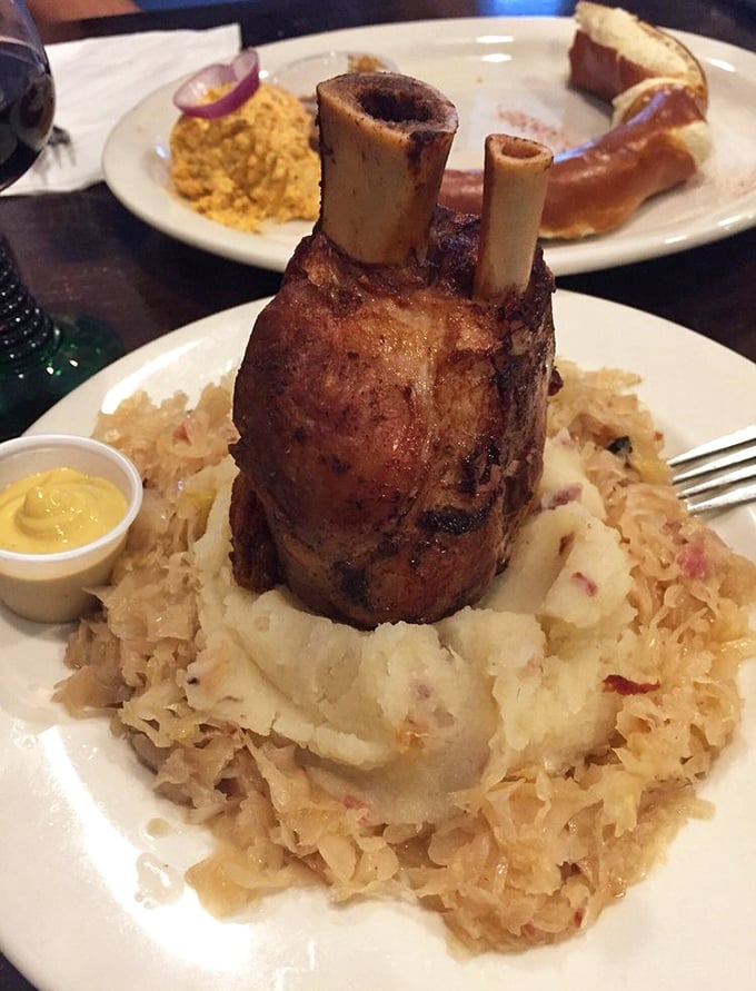 The pork shank arrives like a medieval feast centerpiece—fork-tender meat surrounded by sauerkraut and potatoes, demanding to be photographed before devoured.