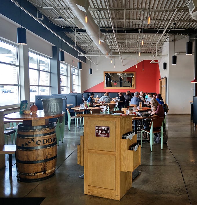 Red accent walls pop against industrial elements, creating a space that feels both contemporary and timeless, like comfort food with a modern twist.