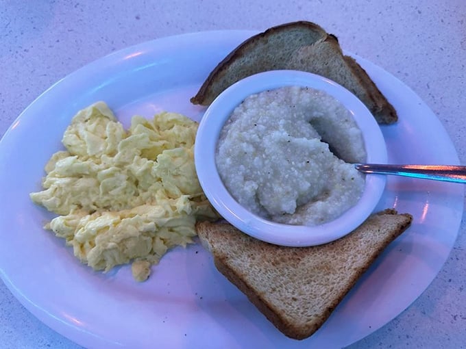 The breakfast trinity: perfectly scrambled eggs, grits that would make any Southern grandmother nod in approval, and toast ready for butter's warm embrace.