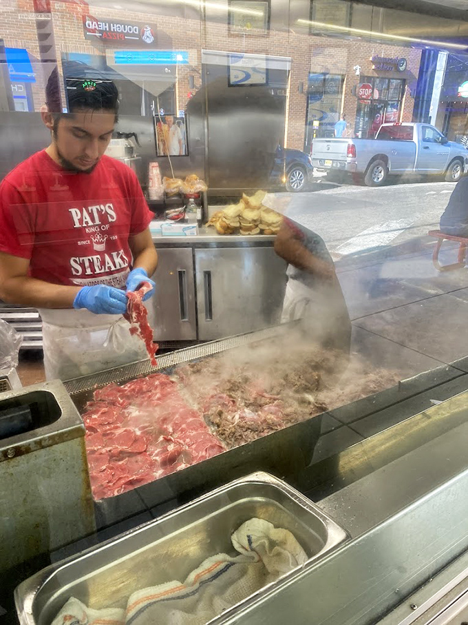 Slicing, chopping, creating—the sacred ritual of cheesesteak preparation unfolds. Those blue-gloved hands hold the culinary fate of dozens.