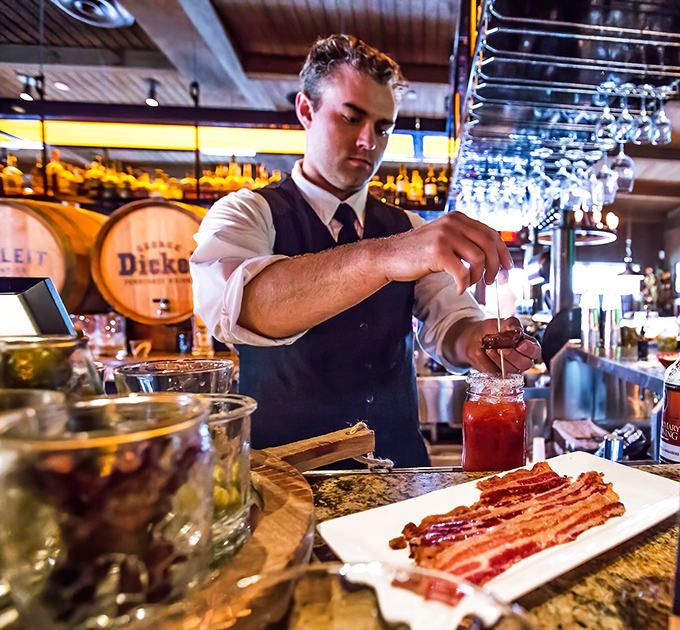 Cocktail craftsmanship in action—where precision meets showmanship and bacon somehow makes perfect sense as a garnish.
