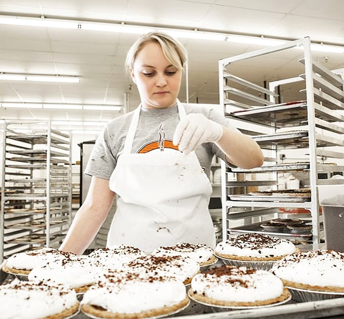 Craftsmanship in action—each pie receives the attention a Renaissance painting deserves. This is where magic happens, one whipped topping at a time.