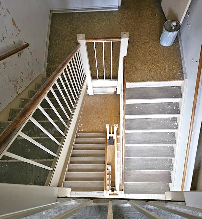 Staircases like these have witnessed countless journeys—both up and down—some voluntary, others decidedly not. The institutional white paint can't hide their stories.