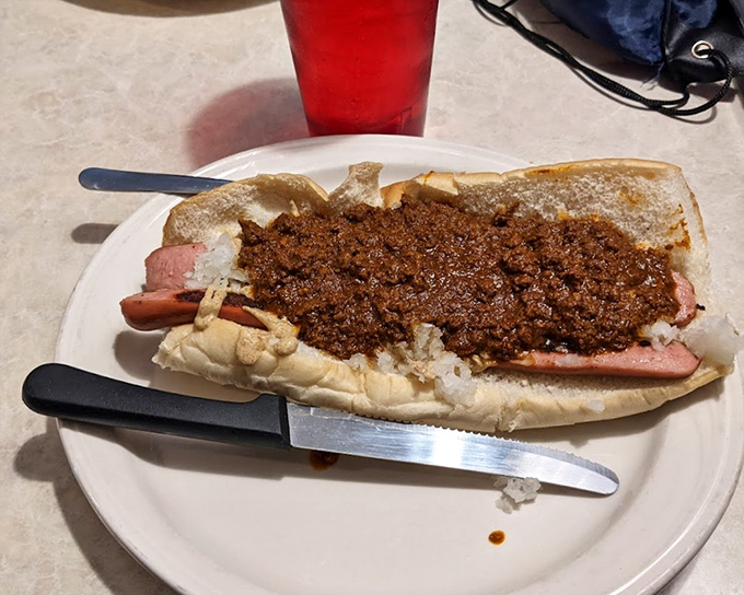 The star attraction in all its glory – a Texas Weiner with that signature chili sauce cascading down the sides. Poetry in hot dog form.