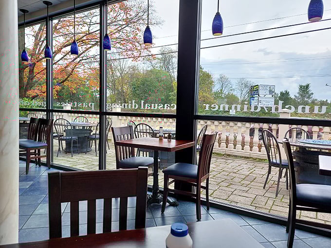 Fall foliage frames the view from inside, creating a seasonal backdrop for your Greek feast. Blue pendant lights echo the Mediterranean theme.
