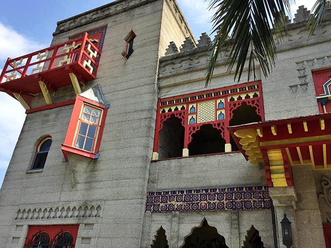 The castle's exterior details reveal themselves in layers—geometric cutouts, colorful tiles, and those signature red accents against concrete that's withstood over a century of Florida weather.