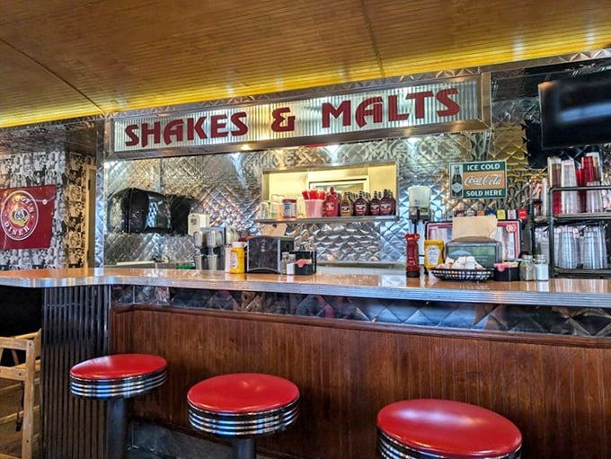 The shake and malt station gleams with promise under vintage signage. Those red counter stools have supported generations of satisfied customers.