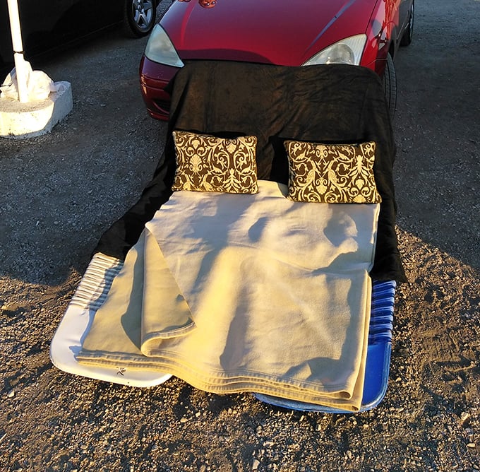 Truck bed transformed into the world's coziest theater seats. These kids have mastered the art of drive-in comfort with pillows, blankets, and smiles.