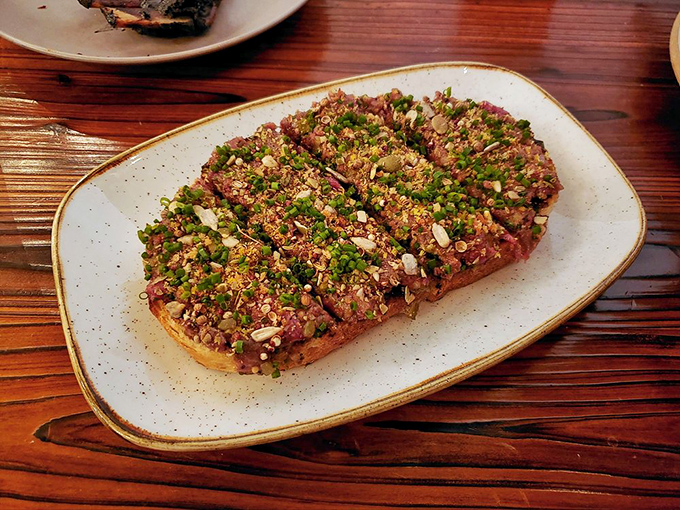 Beef tartare that's dressed to impress. Raw perfection with all the fixings—proof that sometimes cooking is entirely optional.