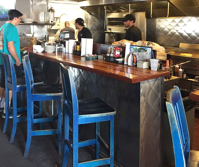 The blue counter stools aren't just seating—they're front-row tickets to culinary theater where seafood is the star and hunger always gets a happy ending.