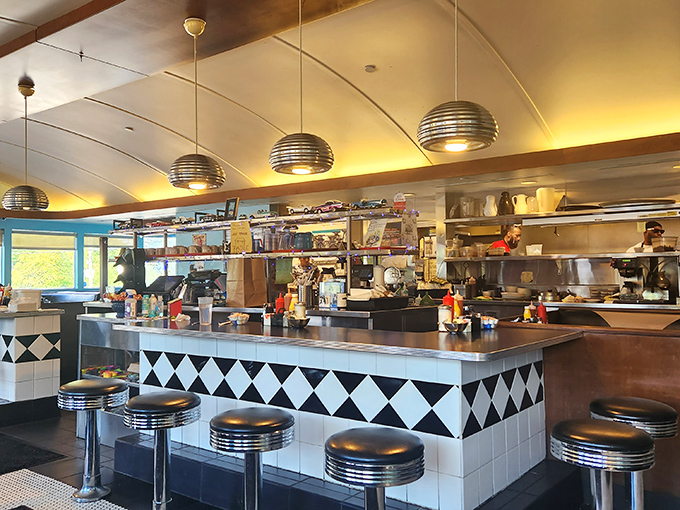 The diner counter—where solo diners become temporary family and the short-order cook performs culinary magic right before your eyes.