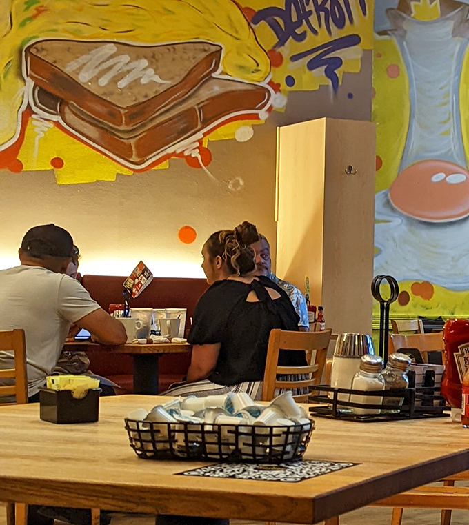 Fellow diners enjoying the communal breakfast experience against a backdrop of Detroit-themed breakfast murals. Morning magic in progress.