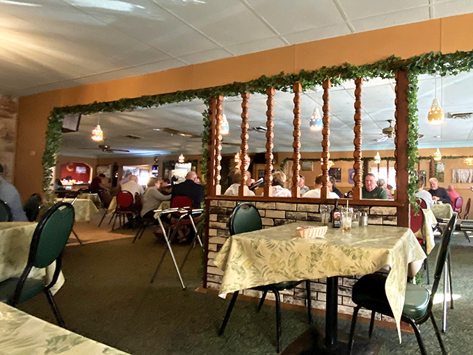 Room dividers adorned with greenery separate dining spaces—creating intimate pockets of conversation in the larger supper club landscape.