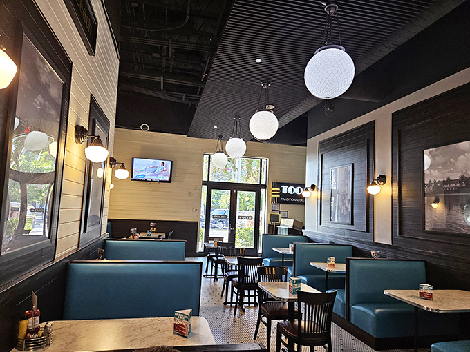 The dining area balances nostalgia and comfort with its blue booths and globe lighting—like a time machine with excellent table service.