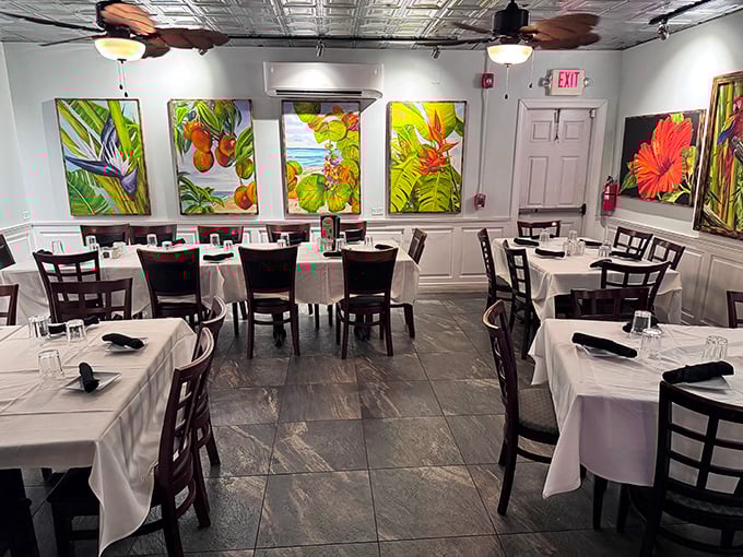 The dining room balances elegance with island casual—white tablecloths say "special occasion" while tropical artwork reminds you flip-flops are perfectly acceptable footwear.