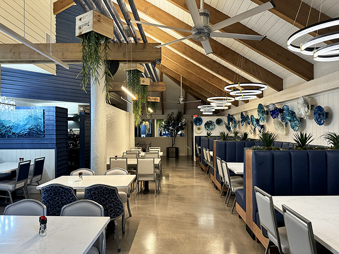 Coastal elegance defined. High ceilings, hanging plants, and ocean-inspired art create a dining room that feels both upscale and approachable.
