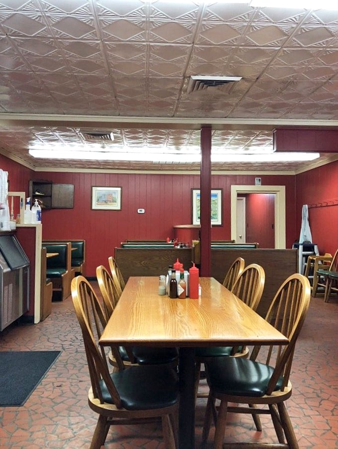 Red walls, pressed tin ceiling, and wooden dividers create barbecue's perfect stage. This isn't decoration—it's the backdrop for edible memories.