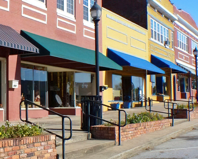 These storefronts with their brick planters and colorful awnings aren't trying to be quaint—they just never stopped being authentic.
