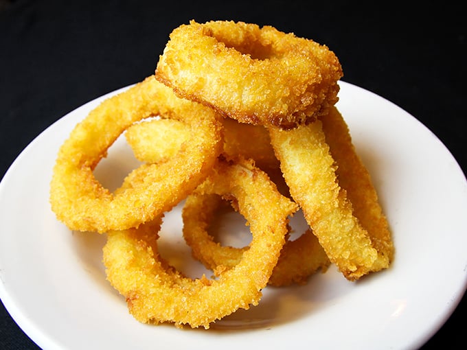Golden-fried onion rings stacked like delicious halos—crispy on the outside, tender within, and impossible to stop eating once you've started.