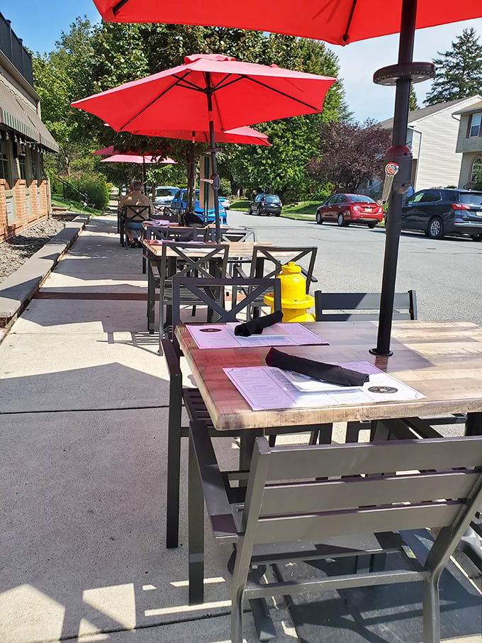 Red umbrellas stand guard over outdoor tables where summer breezes complement the seafood in ways no air conditioning ever could.