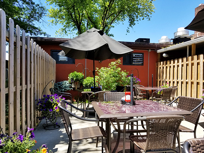 A secret garden patio that feels like dining in a neighbor's backyard. Purple flowers and umbrella shade create the perfect summer breakfast escape.