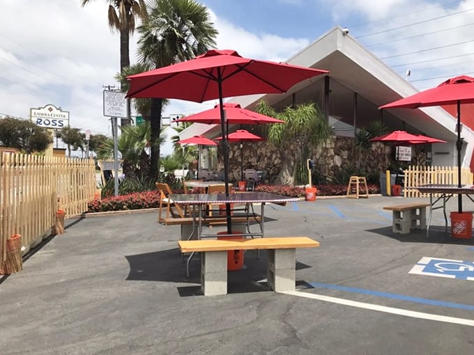 Even the outdoor seating carries that signature splash of red, creating an oasis where palm trees and parasols shield you from the California sun.