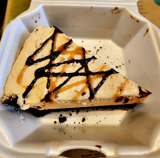 This slice of peanut butter pie isn't just dessert – it's therapy with a crust, drizzled with chocolate and caramel in a to-go container of happiness.