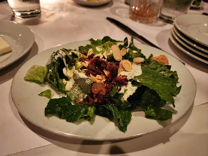 A Caesar salad that actually deserves your attention – crisp romaine, bacon bits, and almonds creating the perfect prelude to protein paradise.