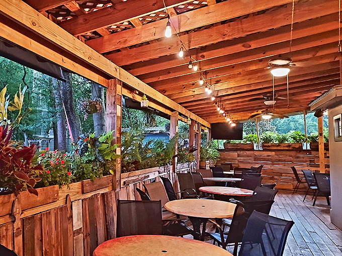 Evening magic happens when string lights illuminate wooden beams. This isn't just outdoor seating—it's dinner theater with trees as the backdrop.