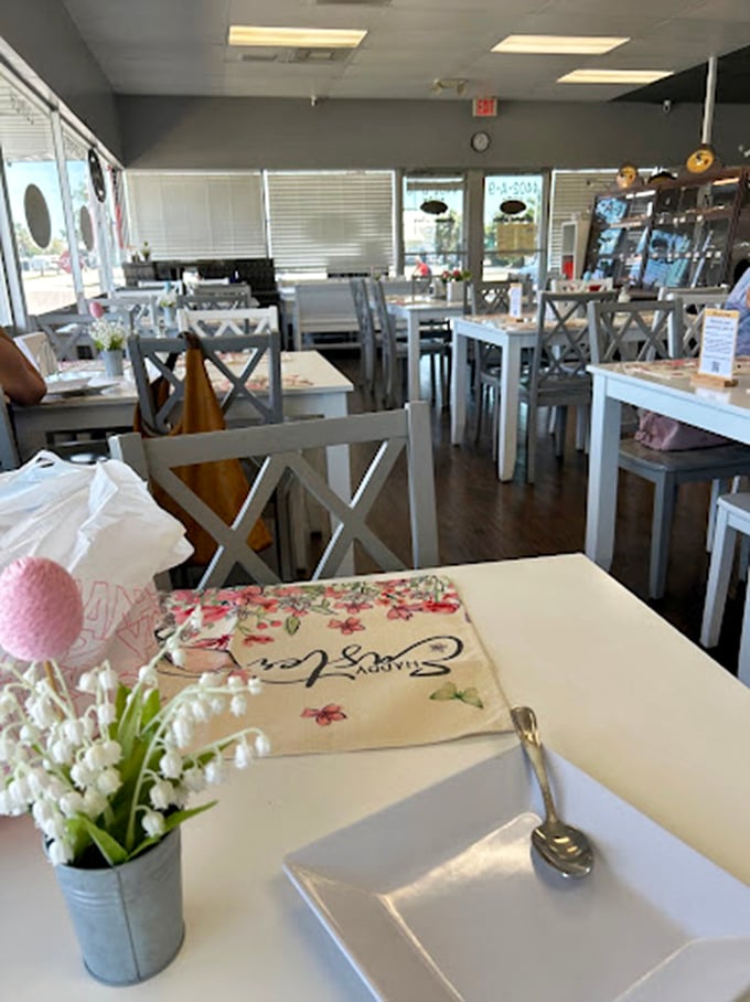 The dining area balances simplicity with charm—white tables, cross-back chairs, and fresh flowers creating a space where the food remains the star.