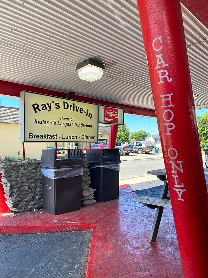 The car hop area features those signature red pillars—architectural marvels that have witnessed decades of Hoosiers experiencing tenderloin-induced happiness.