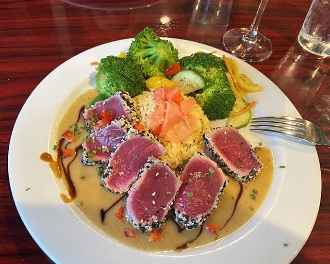 Sesame-crusted ahi tuna, seared rare and sliced to perfection, sits atop a bed of rice surrounded by a rainbow of fresh vegetables.