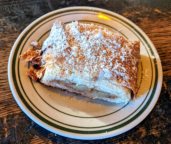 The apple strudel arrives dusted with powdered sugar, its flaky layers promising the perfect sweet ending to your Hungarian-American feast.