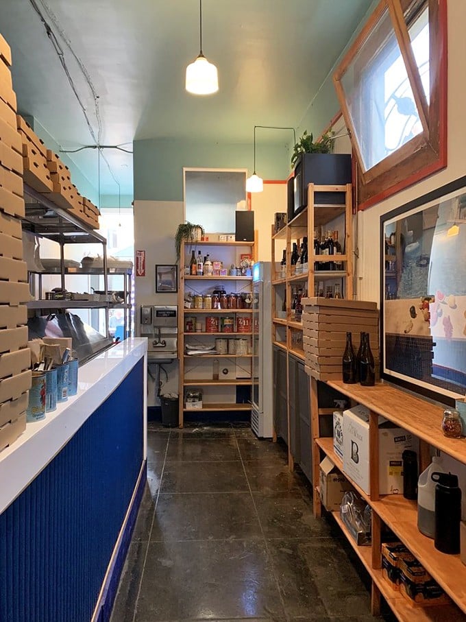 Behind the scenes, organized chaos reigns—stacked pizza boxes and wooden shelves revealing the beautiful simplicity of a restaurant that knows exactly what it's doing.
