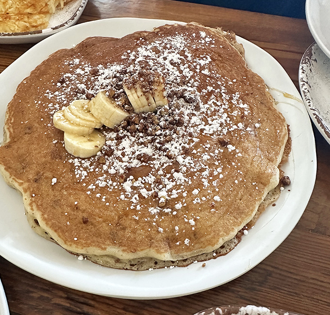 These pancakes don't just include banana—they celebrate it with a dusting of powdered sugar like fresh snow on a Texas morning.