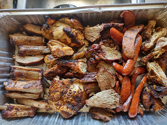A barbecue platter that's basically a family reunion of meats – ribs, chicken, and sausage sharing space with carrots that snuck into the smoker.