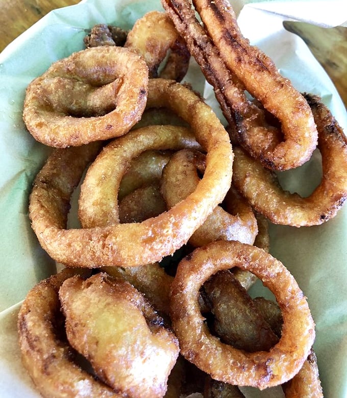 These onion rings aren't just side dishes—they're golden halos of crispy perfection that deserve their own moment of reverence.