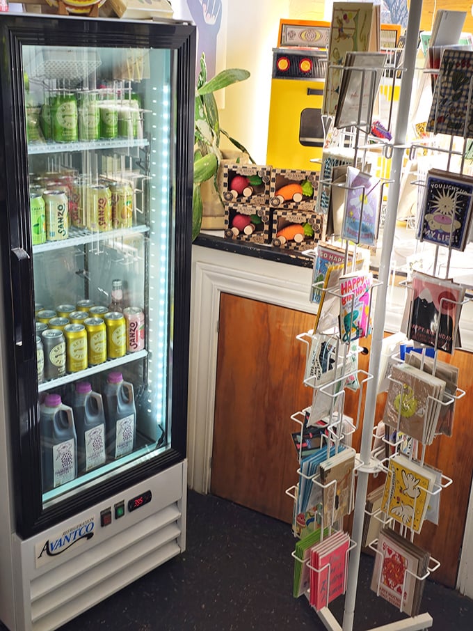 A refrigerator stocked with colorful beverages and a rack of charming cards. Hydration and good wishes—they've thought of everything.