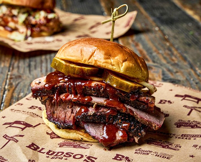 This brisket sandwich isn't just lunch—it's architecture. Layers of smoke-kissed beef with sauce dripping down the sides, held together by a bun that knows its role.