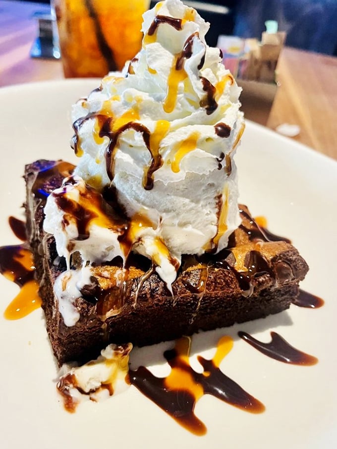 A brownie supporting the weight of ice cream, caramel, and chocolate sauce—the Atlas of the dessert world, carrying sweetness on its shoulders.